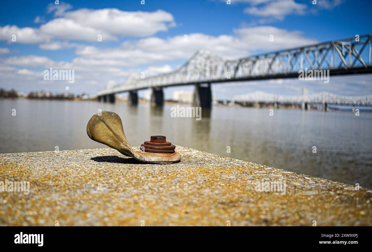 Anchor bolt on rust-stained concrete block with water and bridge in ...