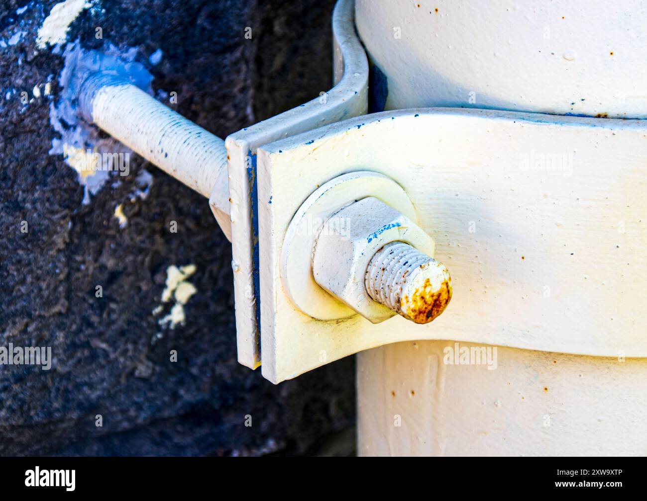 Bolt embedded in concrete holding pipe flange. Bolt head is painted but ...