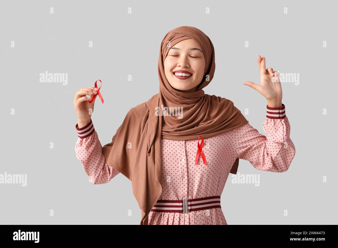 Beautiful Muslim woman with red ribbons on grey background. AID ...