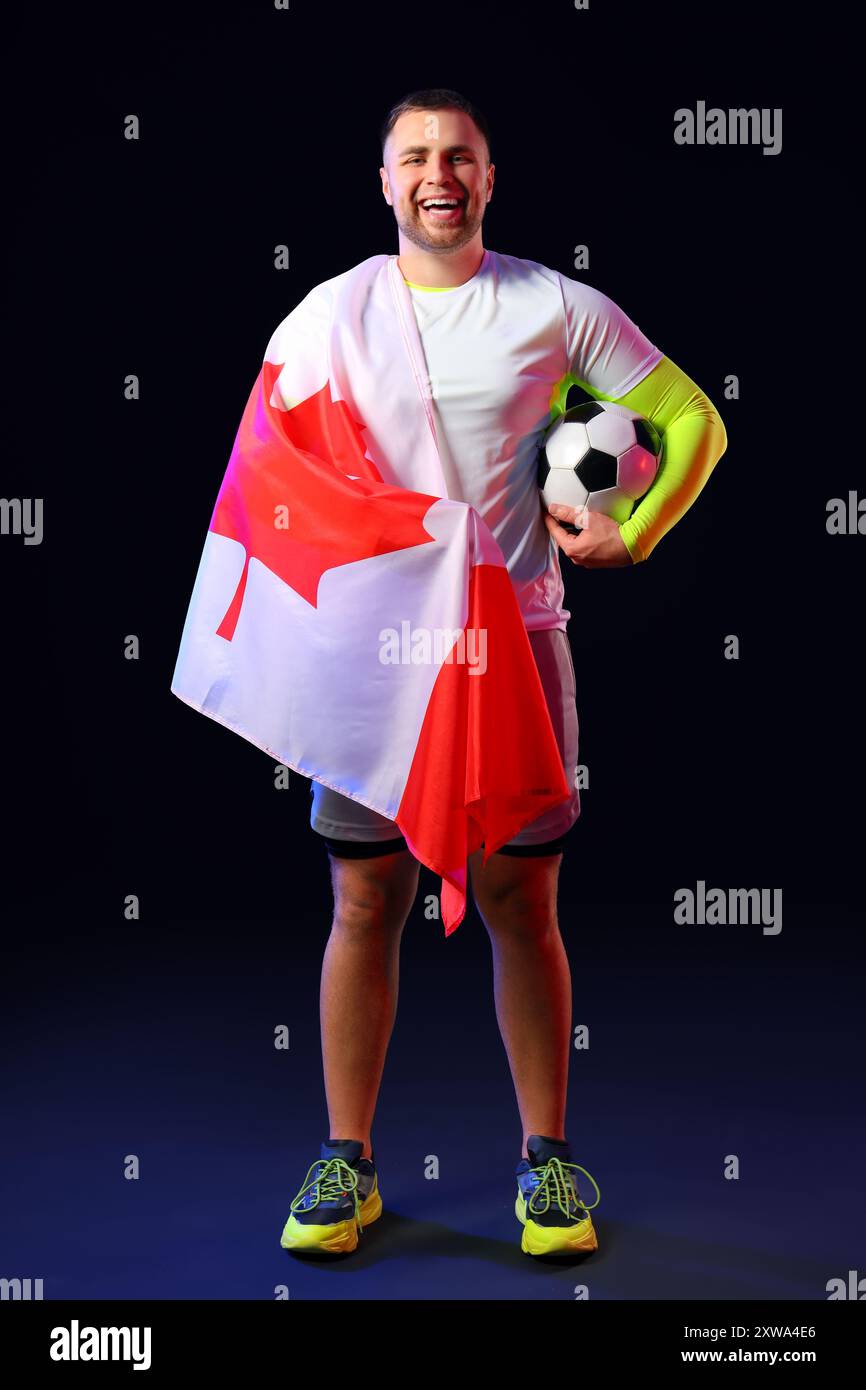 Male footballer with Canadian flag on dark background Stock Photo - Alamy