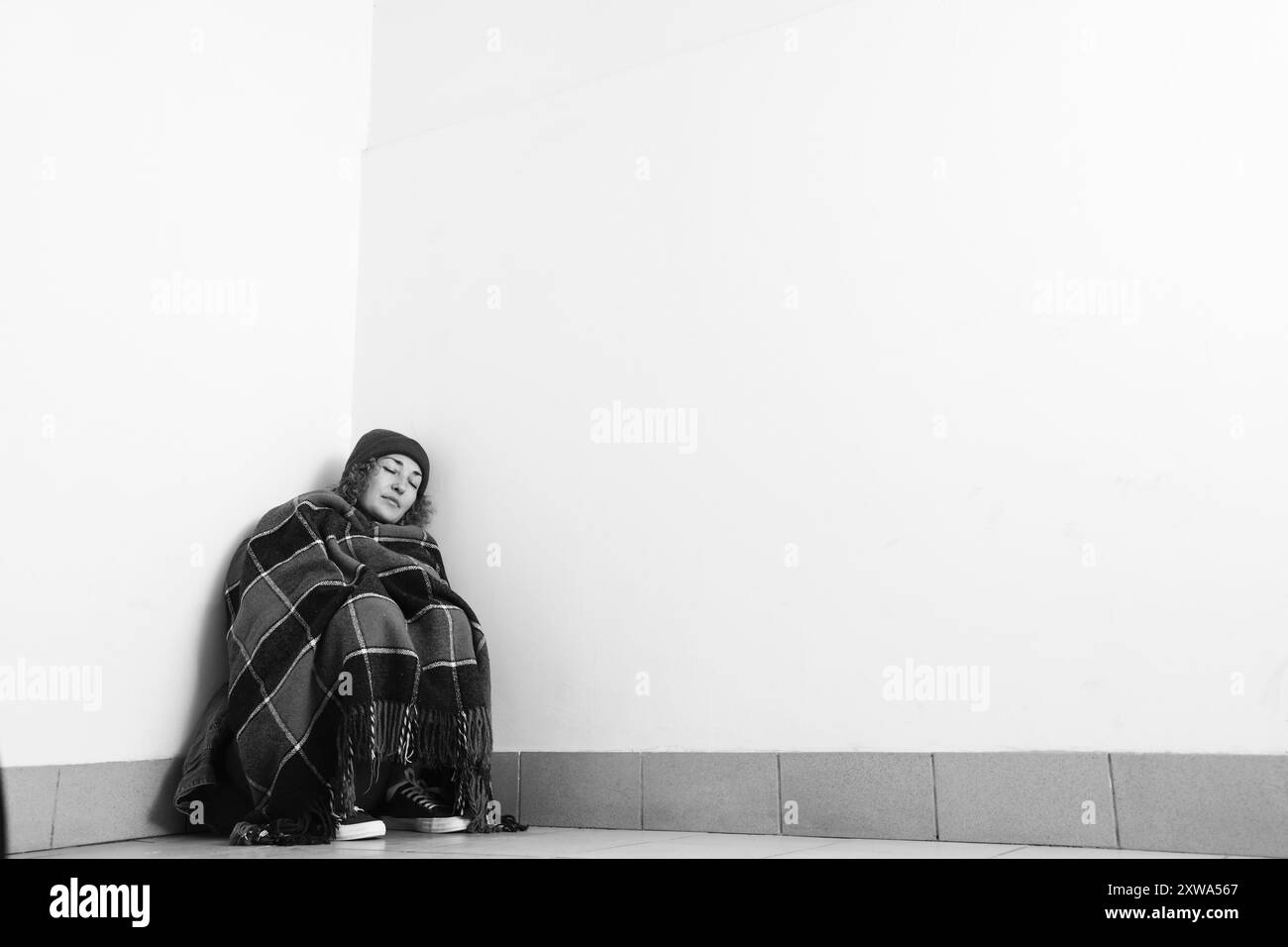 Mature homeless woman with plaid sitting in corner Stock Photo - Alamy