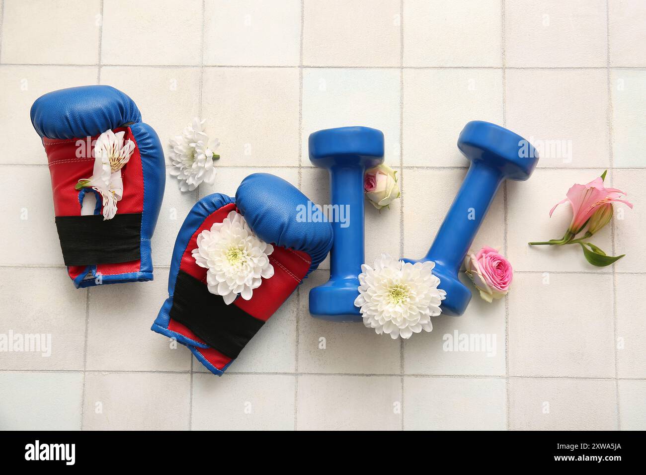Composition with boxing gloves, dumbbells and flowers on light tile ...