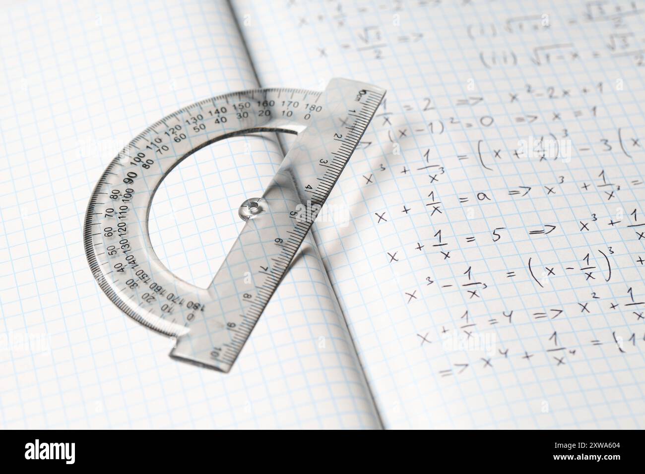 Copybook with handwritten maths formulas and semicircular protractor as ...