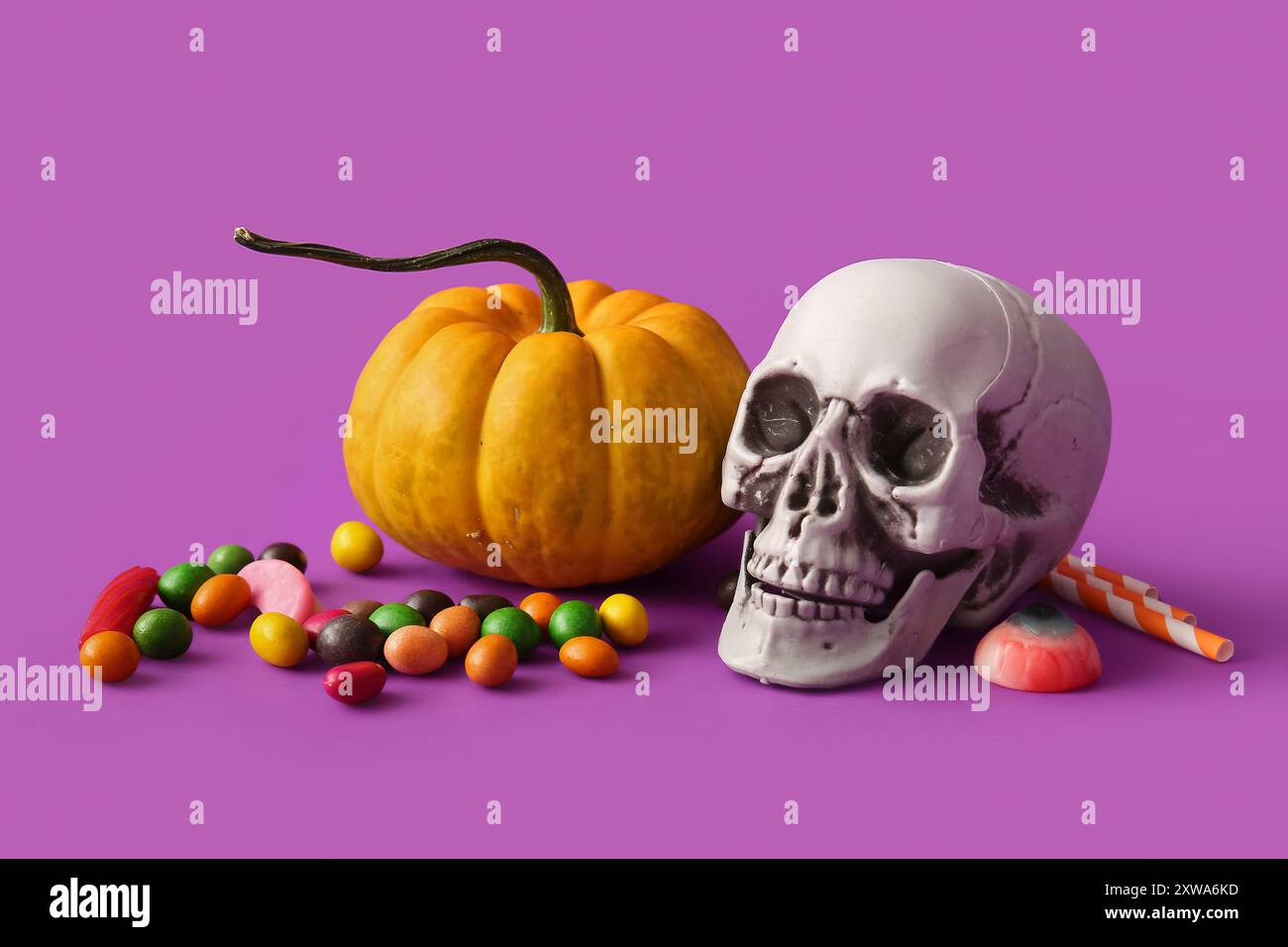 Human skull, pumpkin and candies for Halloween on purple background ...