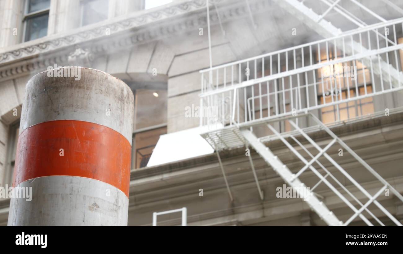 Steam vapor vented on New York City street, orange vapour tube stack ...