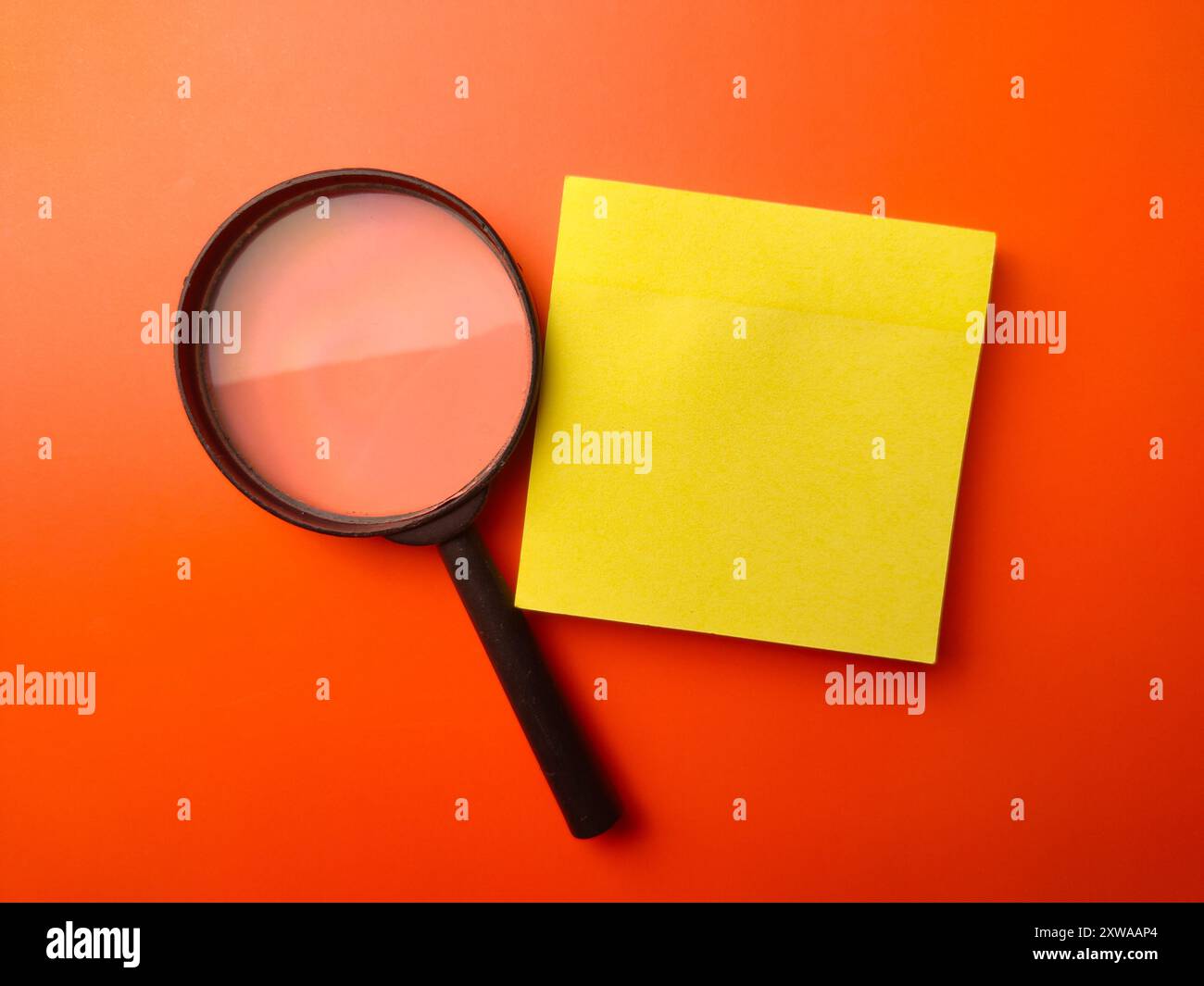 Top view sticky note and magnifying glass on a orange background with ...
