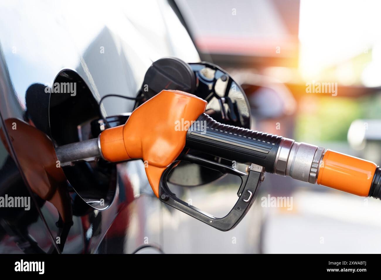 Fuel nozzle inserted in car's gas tank as it's being refueled at gas ...