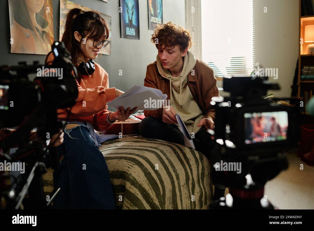 Two young individuals collaborating on a film project in a cozy room ...