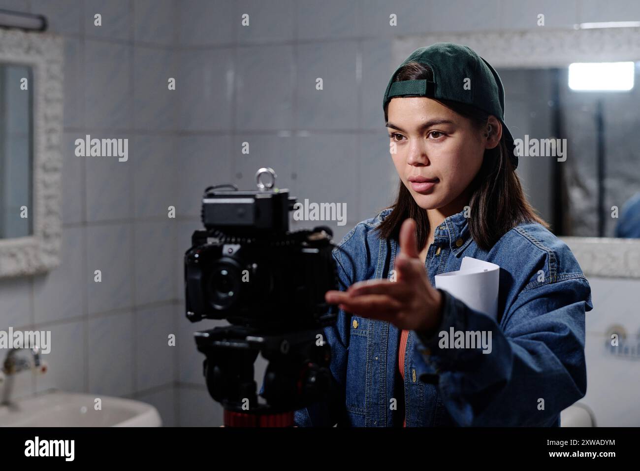 Woman adjusting camera with a flashlight attachment in tiled bathroom ...