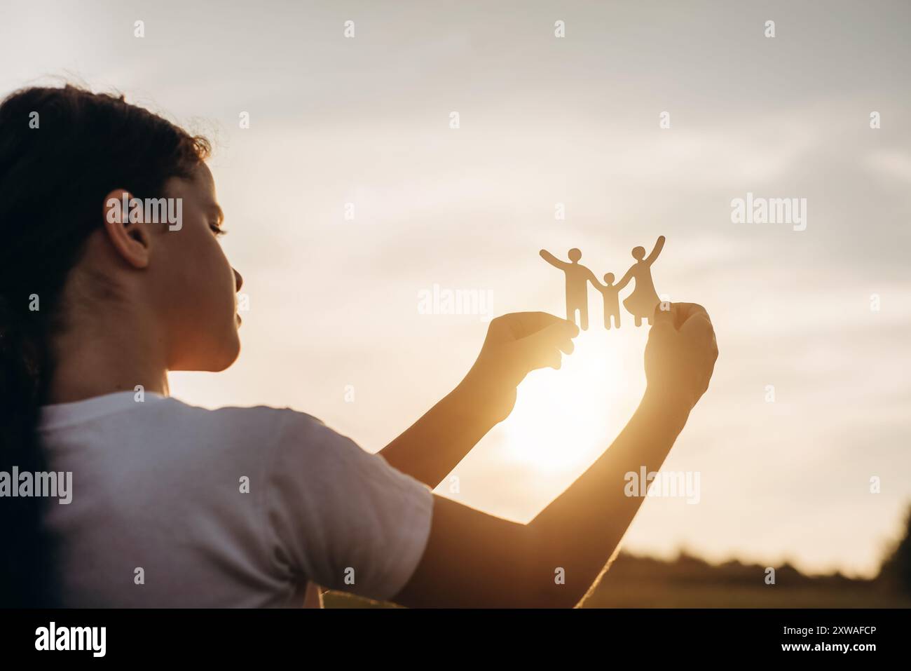 Side view of preteen girl holding paper family cutout on background ...