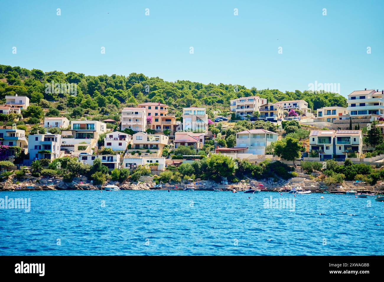 Seaside town with colorful coastal houses on hillside with boats docked ...