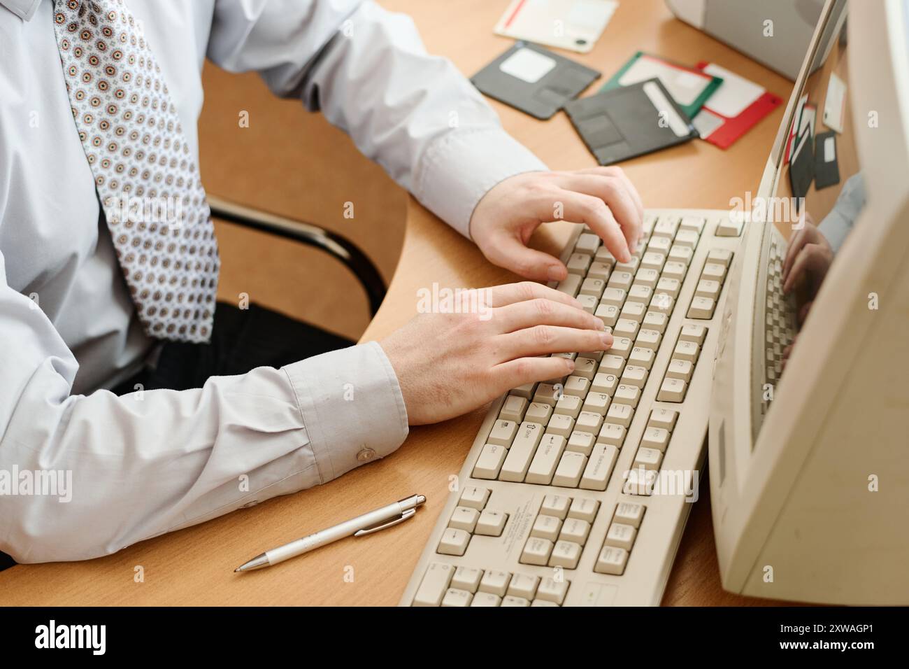Person in formal attire typing on computer keyboard in office setting ...
