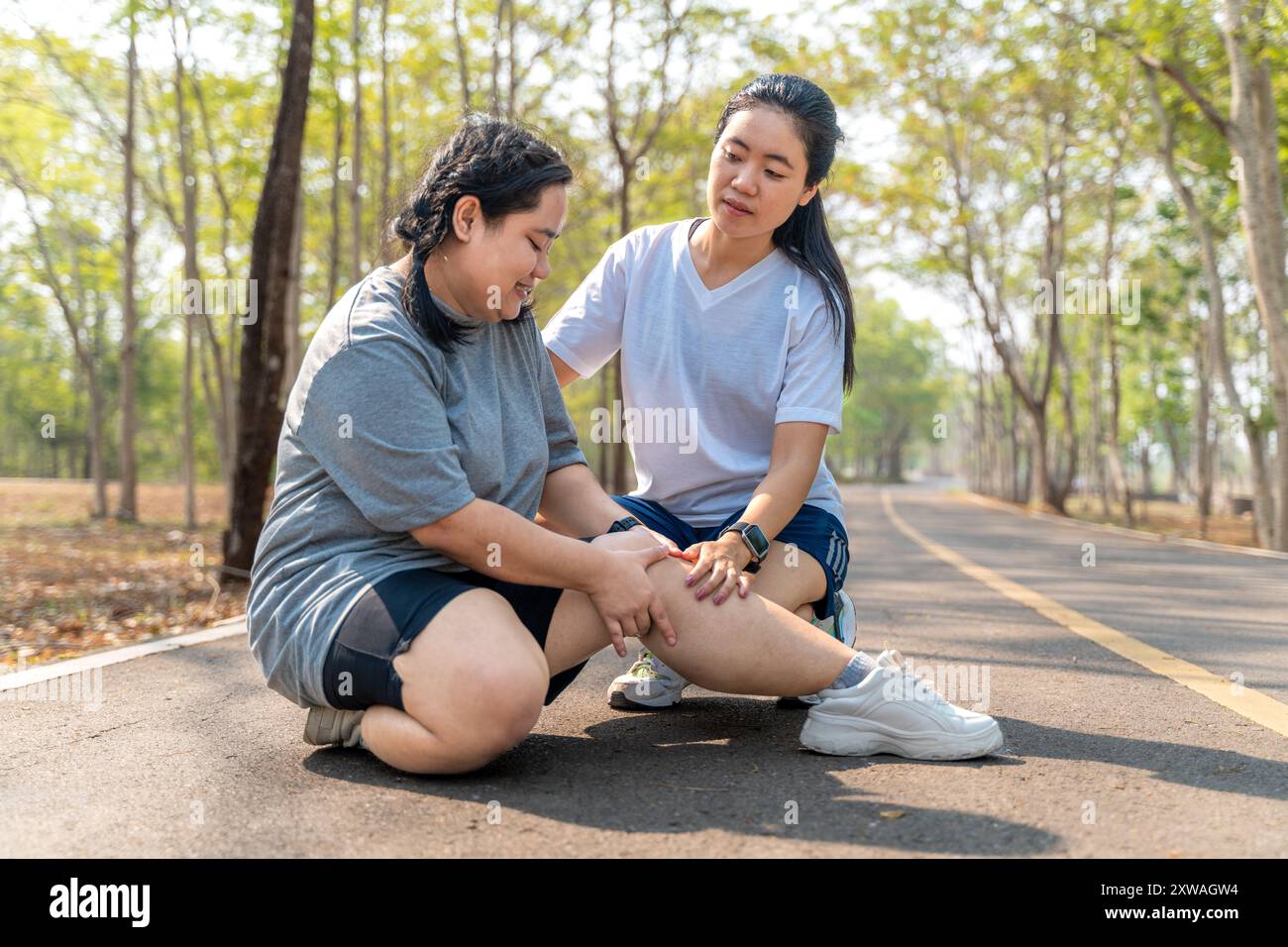 Overweight woman with knee injury sitting on the running track at a ...