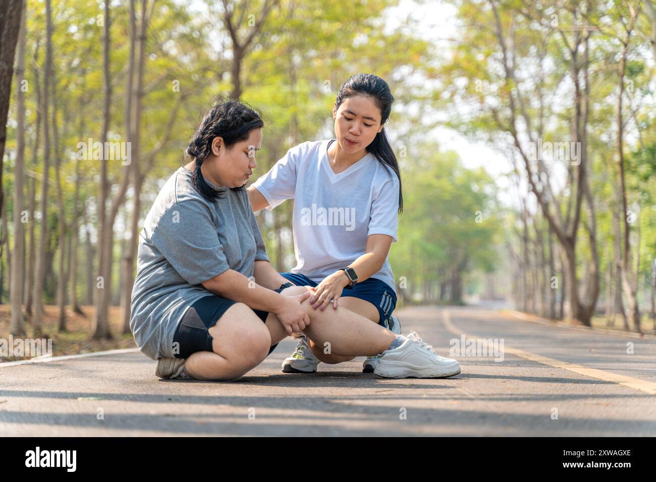 Overweight woman with knee injury sitting on the running track at a ...