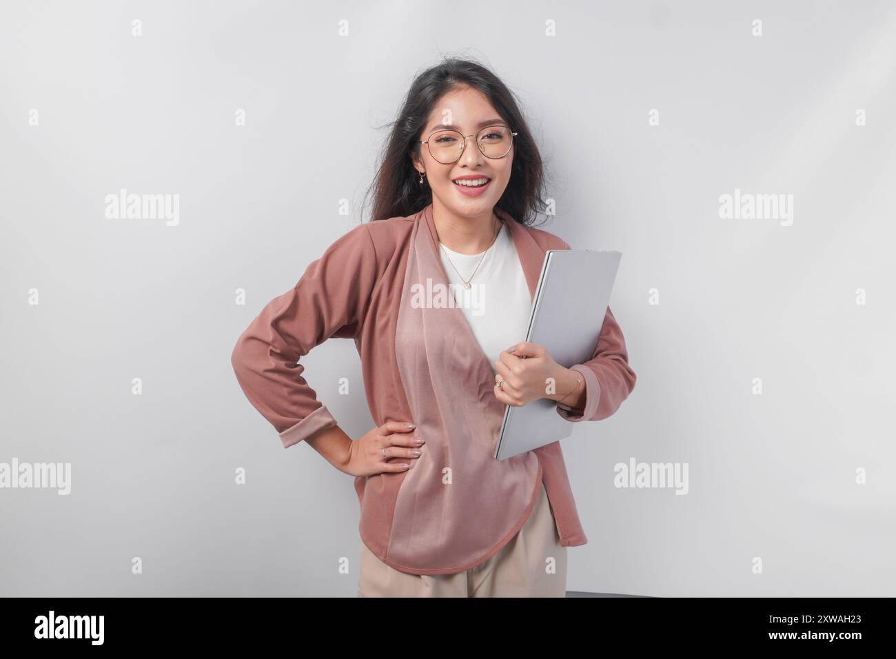 Smiling Asian business woman holding laptop with full confidence pose ...