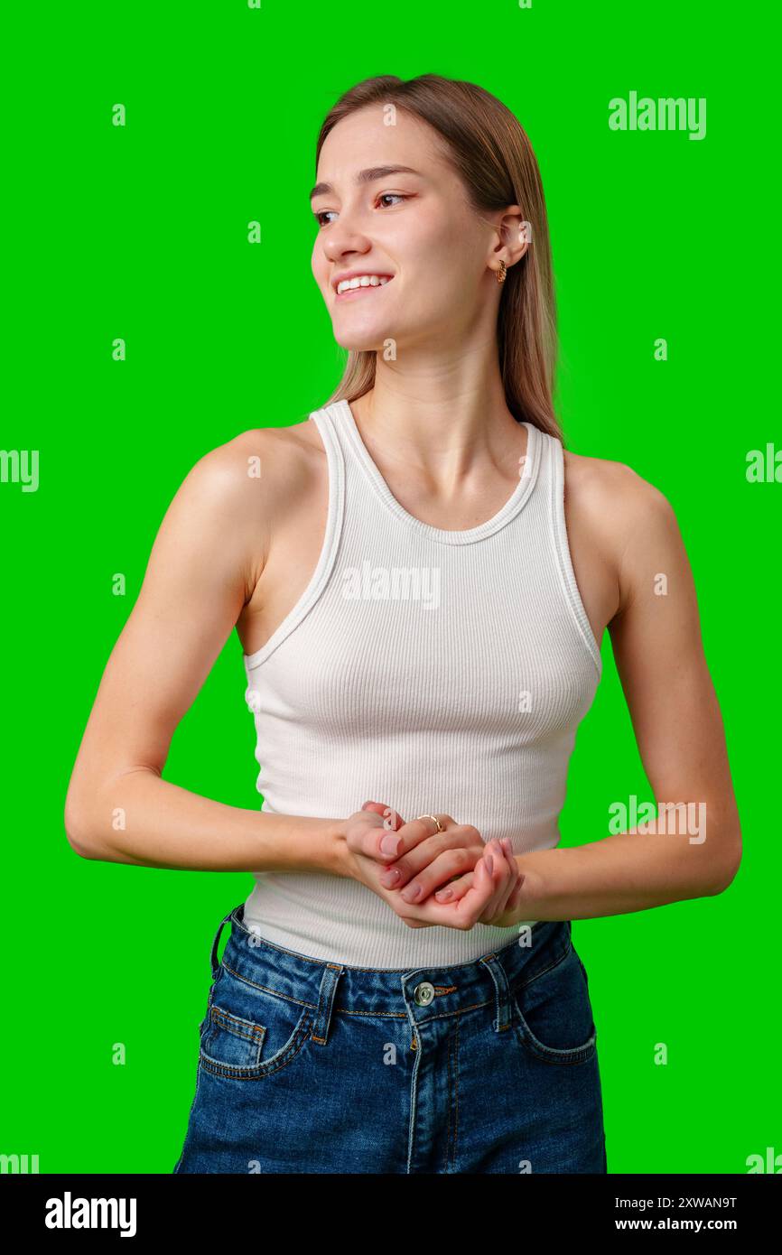 Young Woman in White Tank Top and Blue Jeans Stands Before Green Screen ...