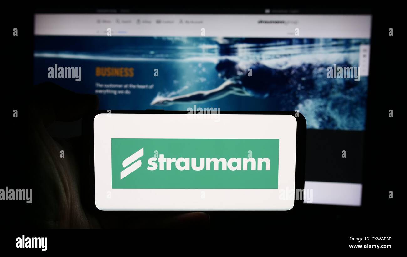 Person holding cellphone with logo of Swiss medical devices company ...