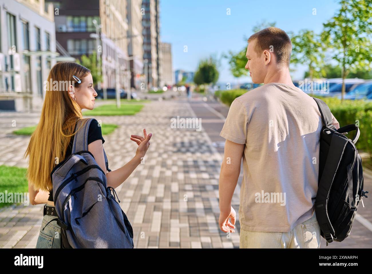 Guy and girl, college students walking together along street of city ...