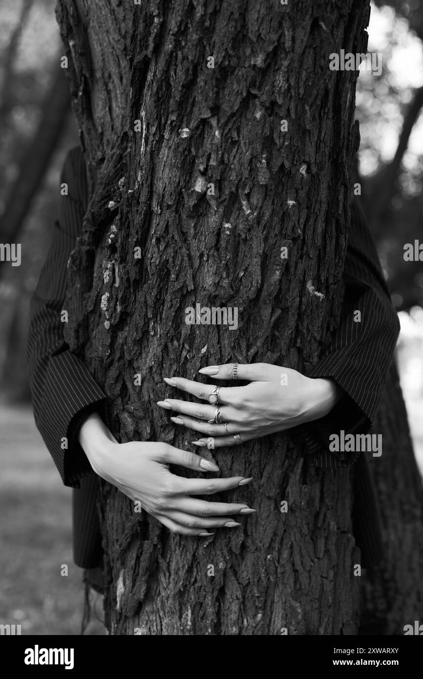 A black and white image of a person hugging a tree trunk with their ...
