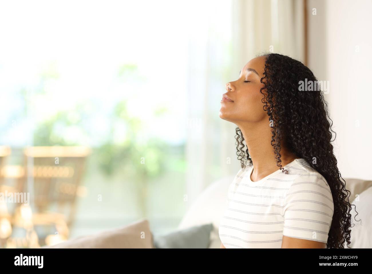 Side view portrait of a black woman breathing at home and relaxing ...