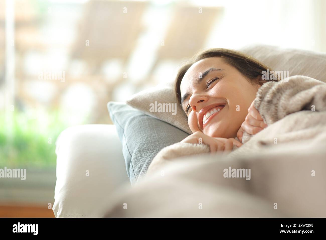 Happy woman napping grabbing blanket at home lying on a couch Stock ...
