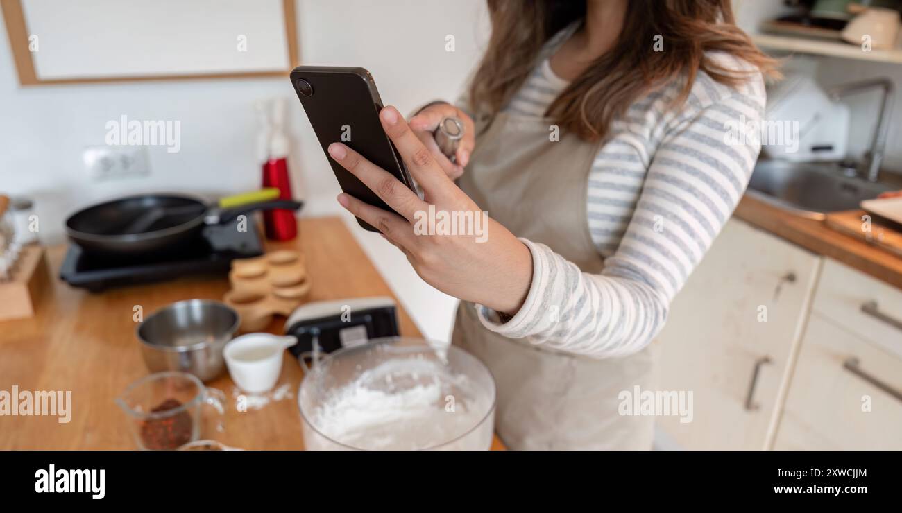 Woman Following Recipe on Smartphone While Baking at Home Stock Photo ...
