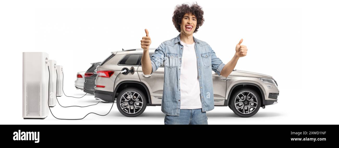 Happy young man gesturing thumbs up at EV charging station isolated on ...