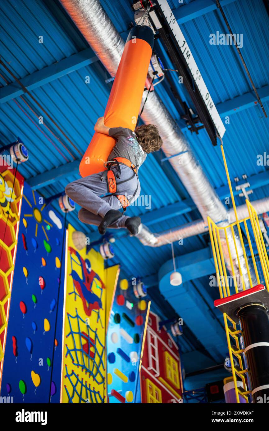 happy boy with a harness training in the rock climbing room. Family ...