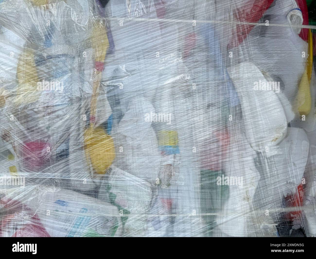 A tightly packed bale of mixed plastic bottles and containers wrapped ...