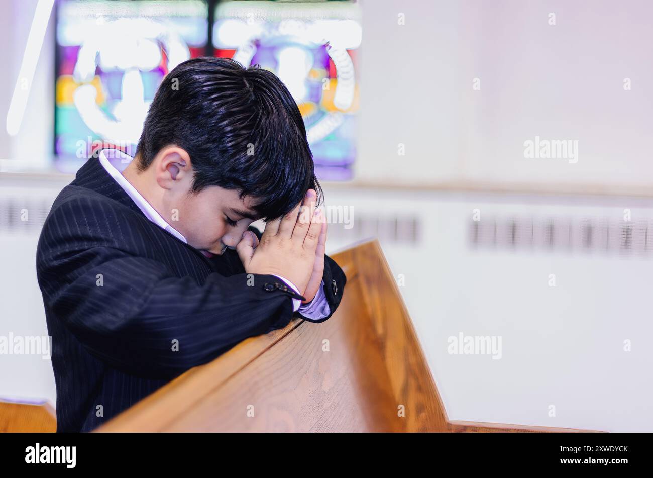 Child boy of Latin American descent praying in Catholic church Stock ...