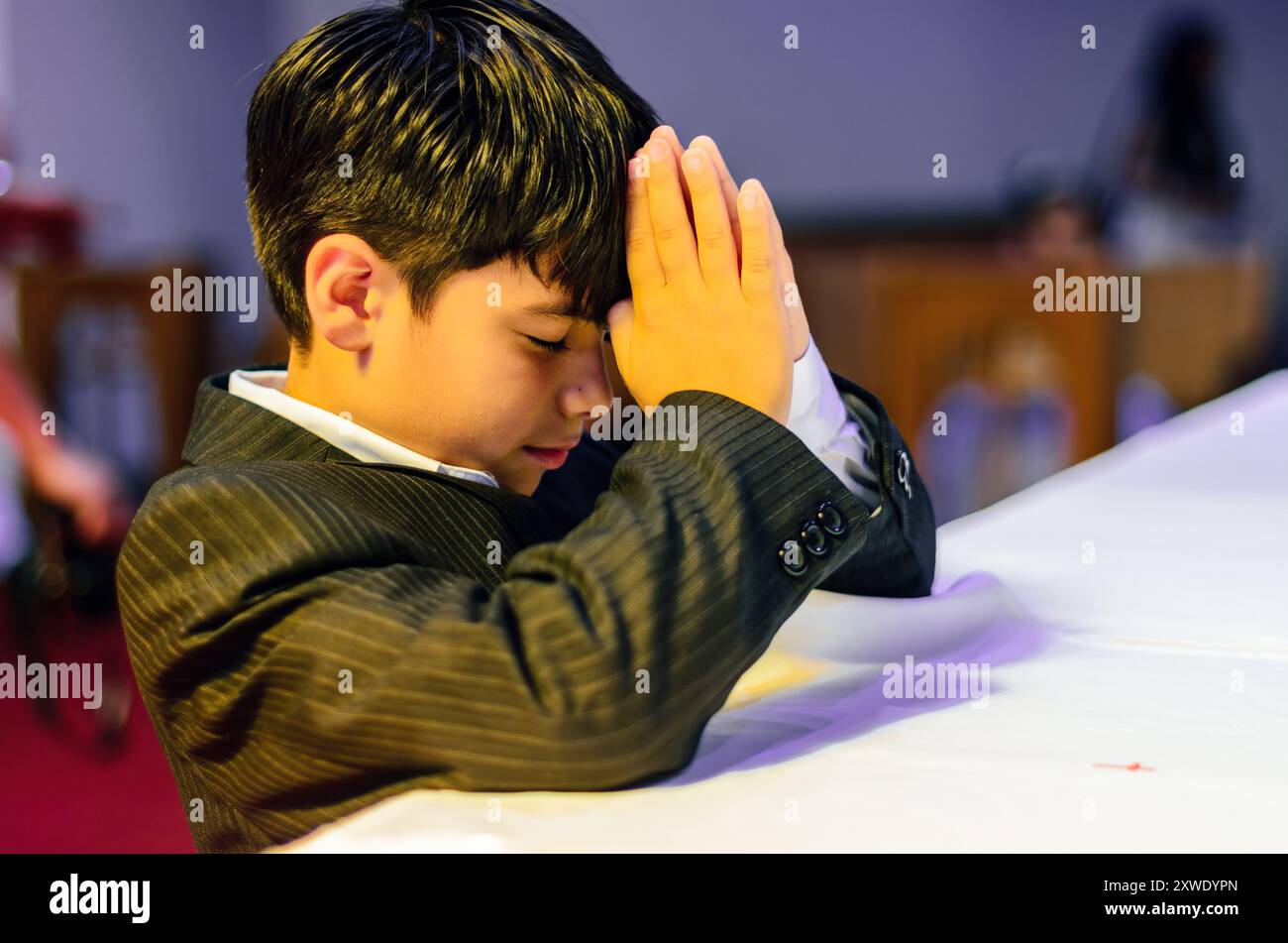 Child boy of Latin American descent praying in Catholic church Stock ...