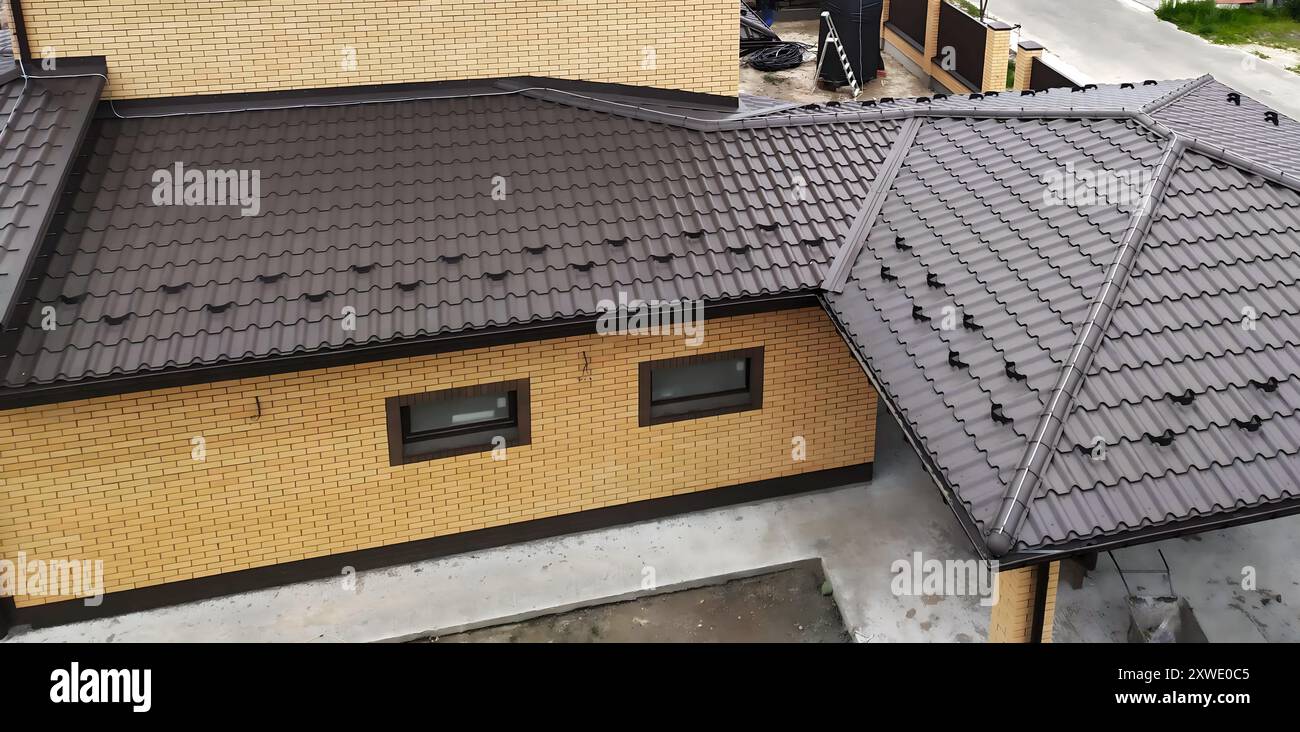 Close-up house roof with steel roofing sheet. Brown modular tile effect ...