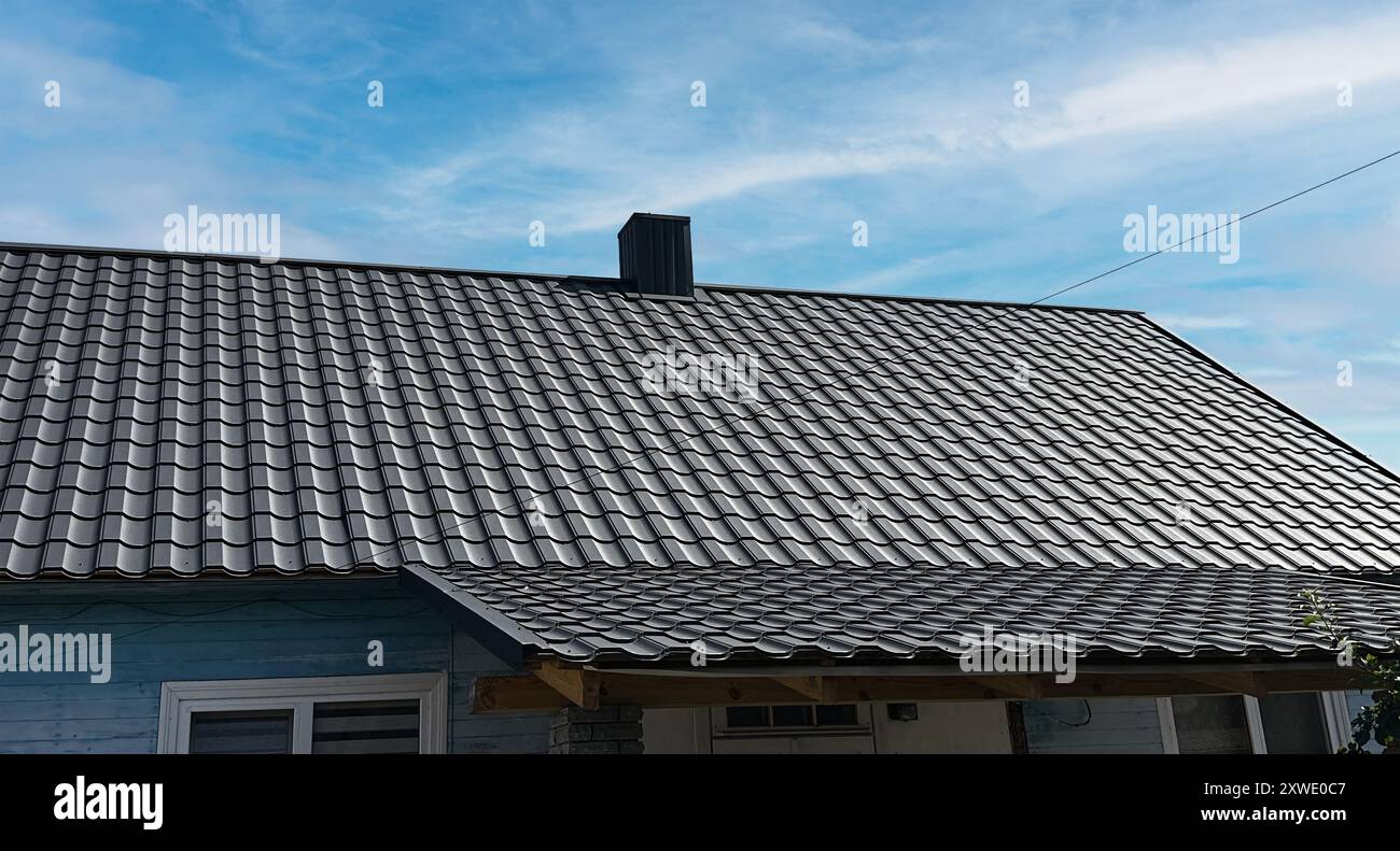 Close-up house roof with steel roofing sheet. Black modular tile effect ...