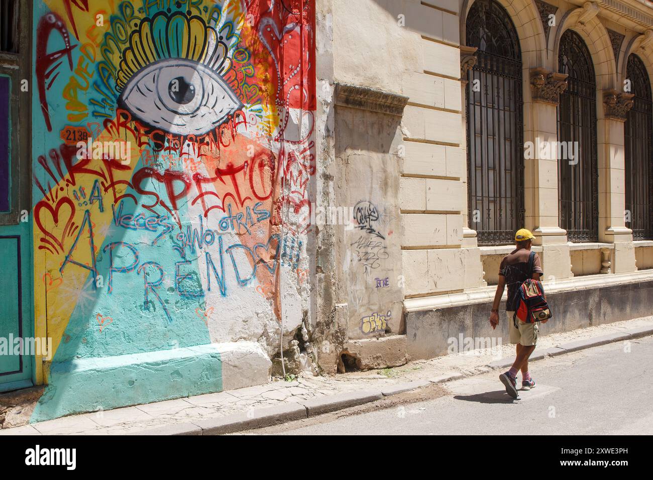 Cuban man walking by urban art and weathered facade, Havana Stock Photo ...