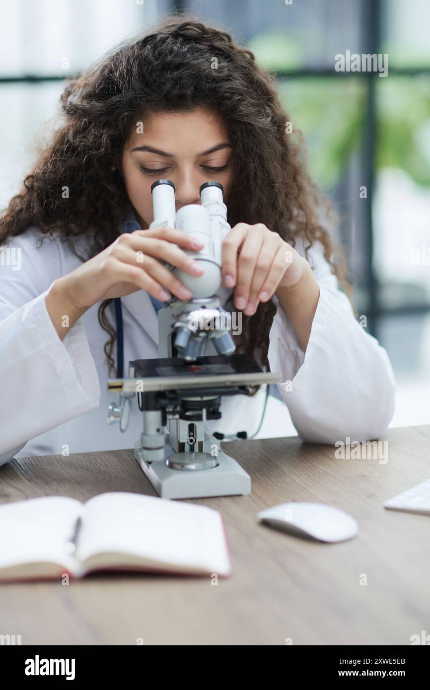 Attractive female scientist looking through a microscope Stock Photo ...