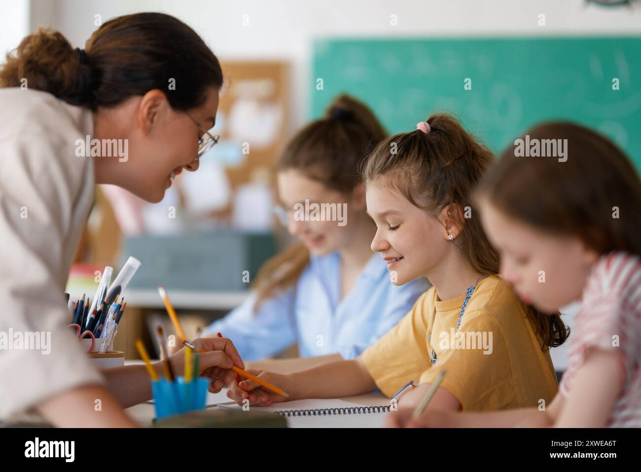 Happy kids and teacher at school. Woman and children are working in the ...