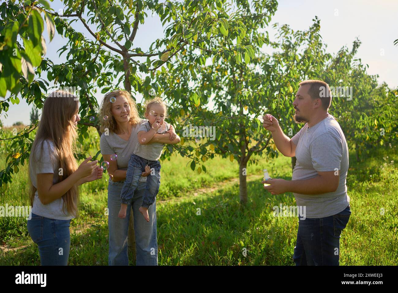 family of four is playing catch bubbles in the garden Stock Photo - Alamy