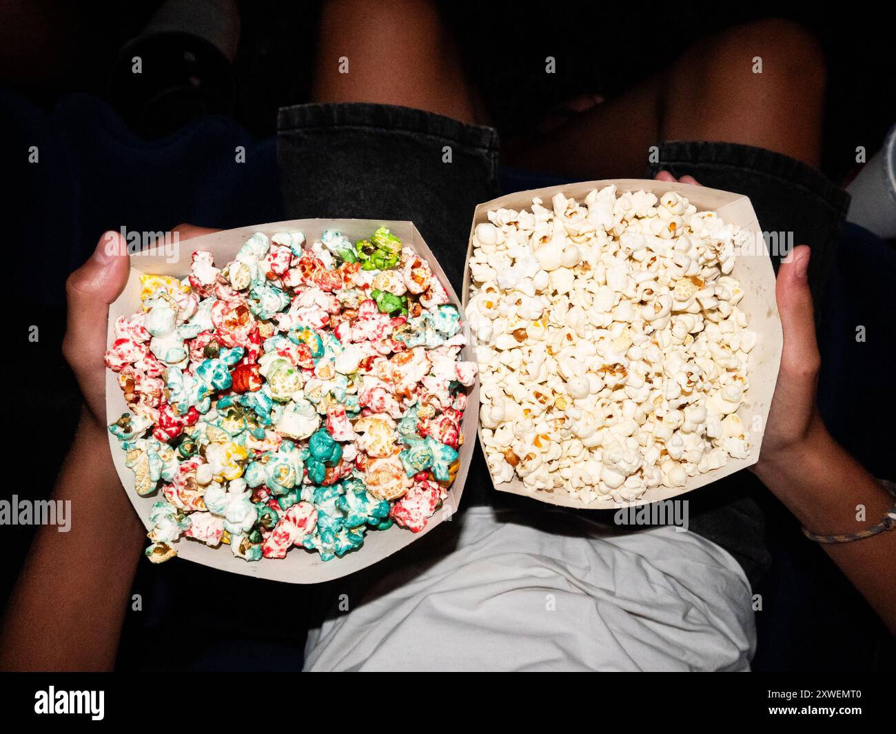 Boy holding two containers of popcorn, one filled with sweet and ...