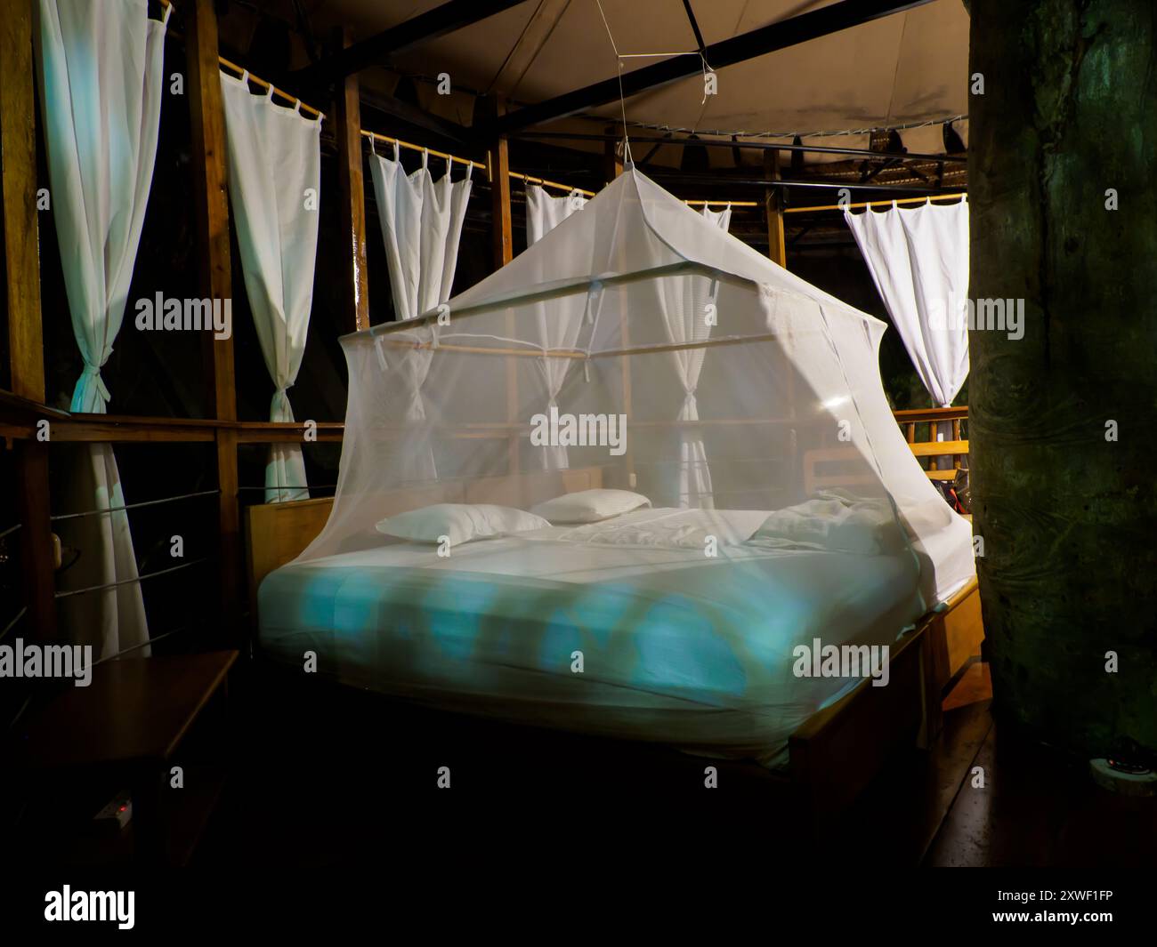 Huge bed with white mosquito net. Glamping accommodation in the Amazon ...