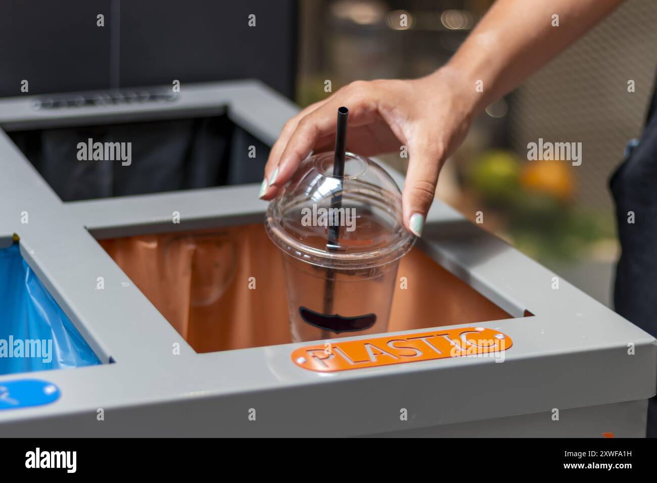 A hand throwing an empty cup in the plastic recycle bin Stock Photo - Alamy