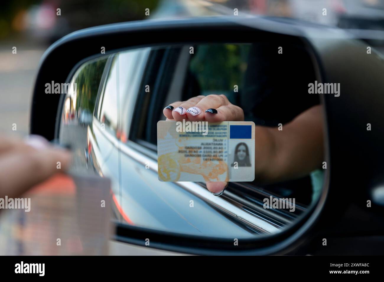Teenager girl showing his driver's license in the car window after ...