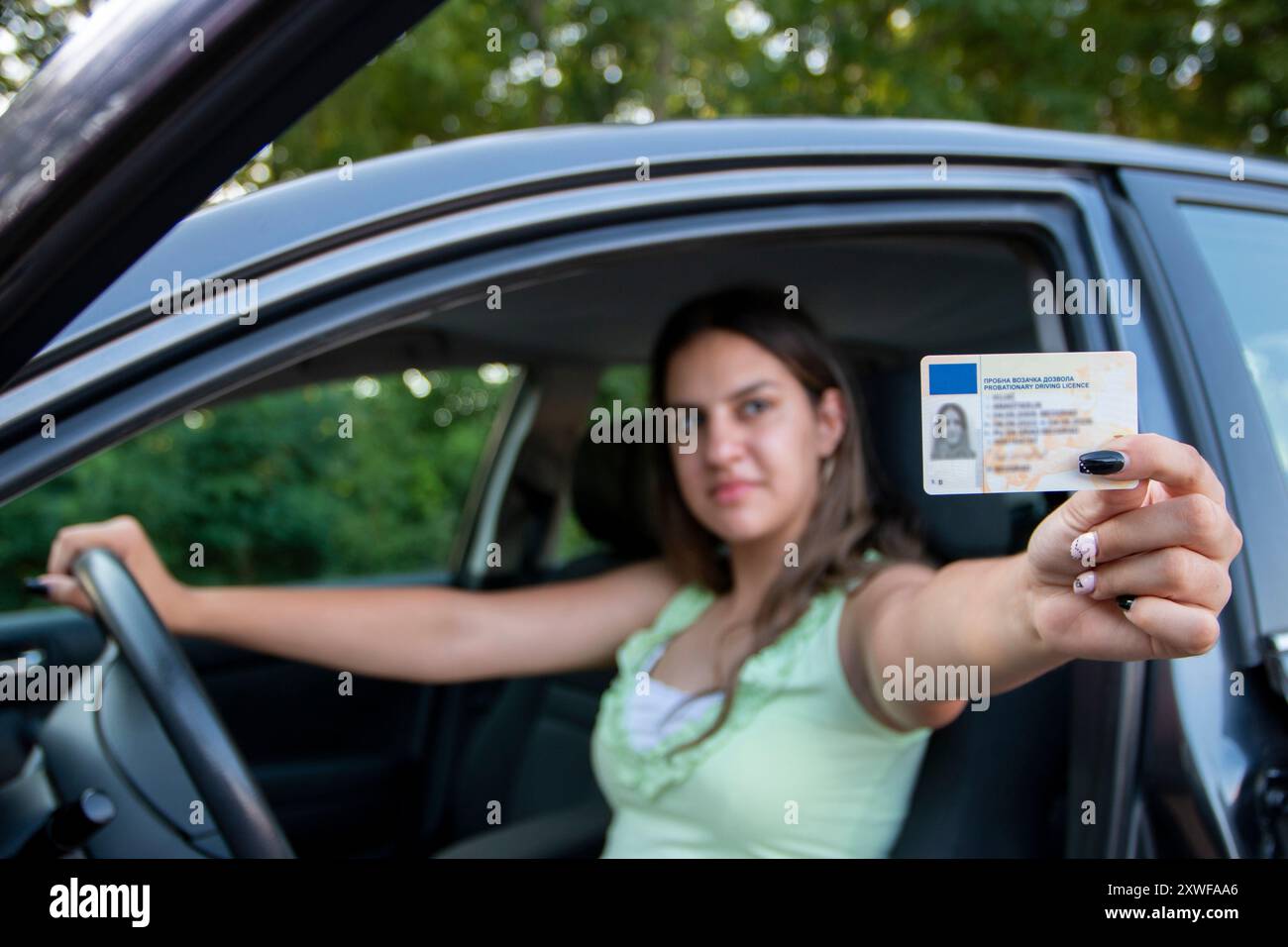 Teenager girl showing his driver's license in the car window after ...