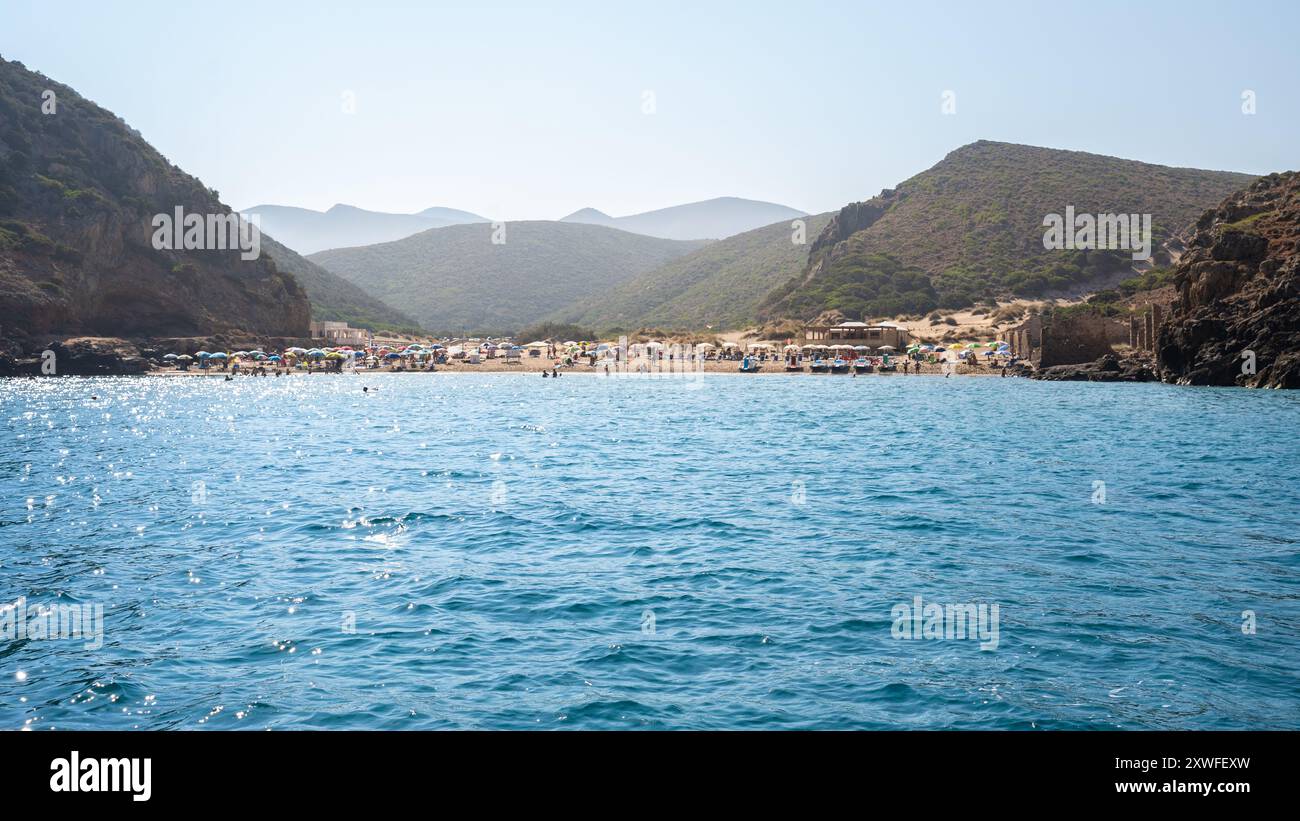 View from a boat of Cala Domestica, a unspoiled cove with with people ...