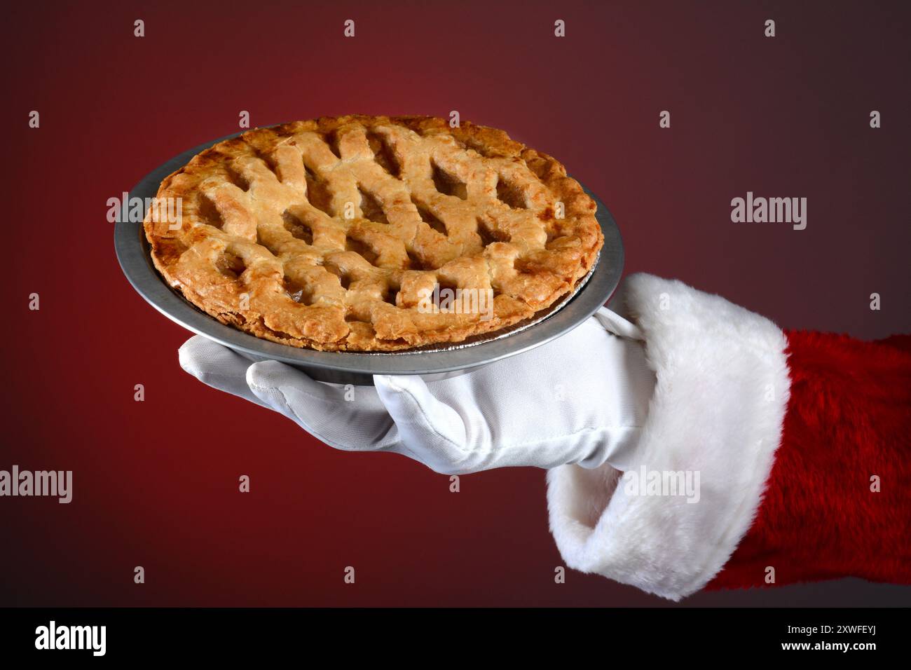 Santa Claus hand holding a fresh baked apple pie over a light to dark ...