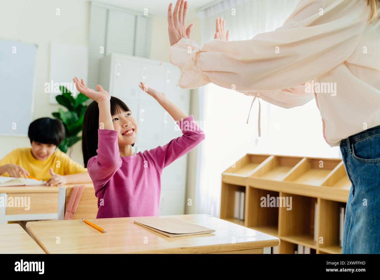 Joyful Asian primary student celebrating achievement with teacher ...