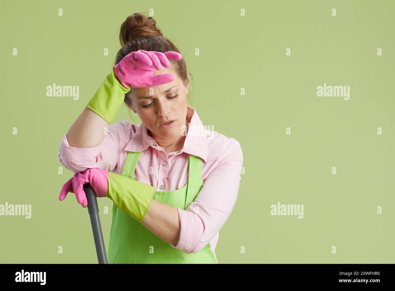 Spring cleaning. sad modern middle aged woman in green apron and rubber ...