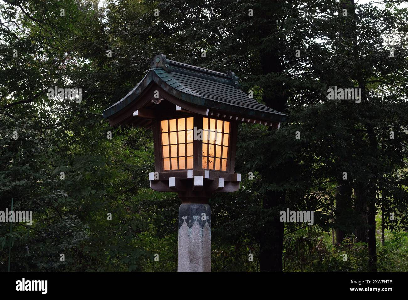 A traditional lamp is lit on the path leading to Meji Shrine in Tokyo ...