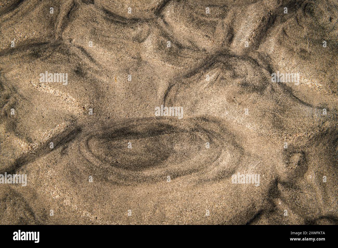 A close up abstract HDR of patterns in the pale and dark sand left by ...
