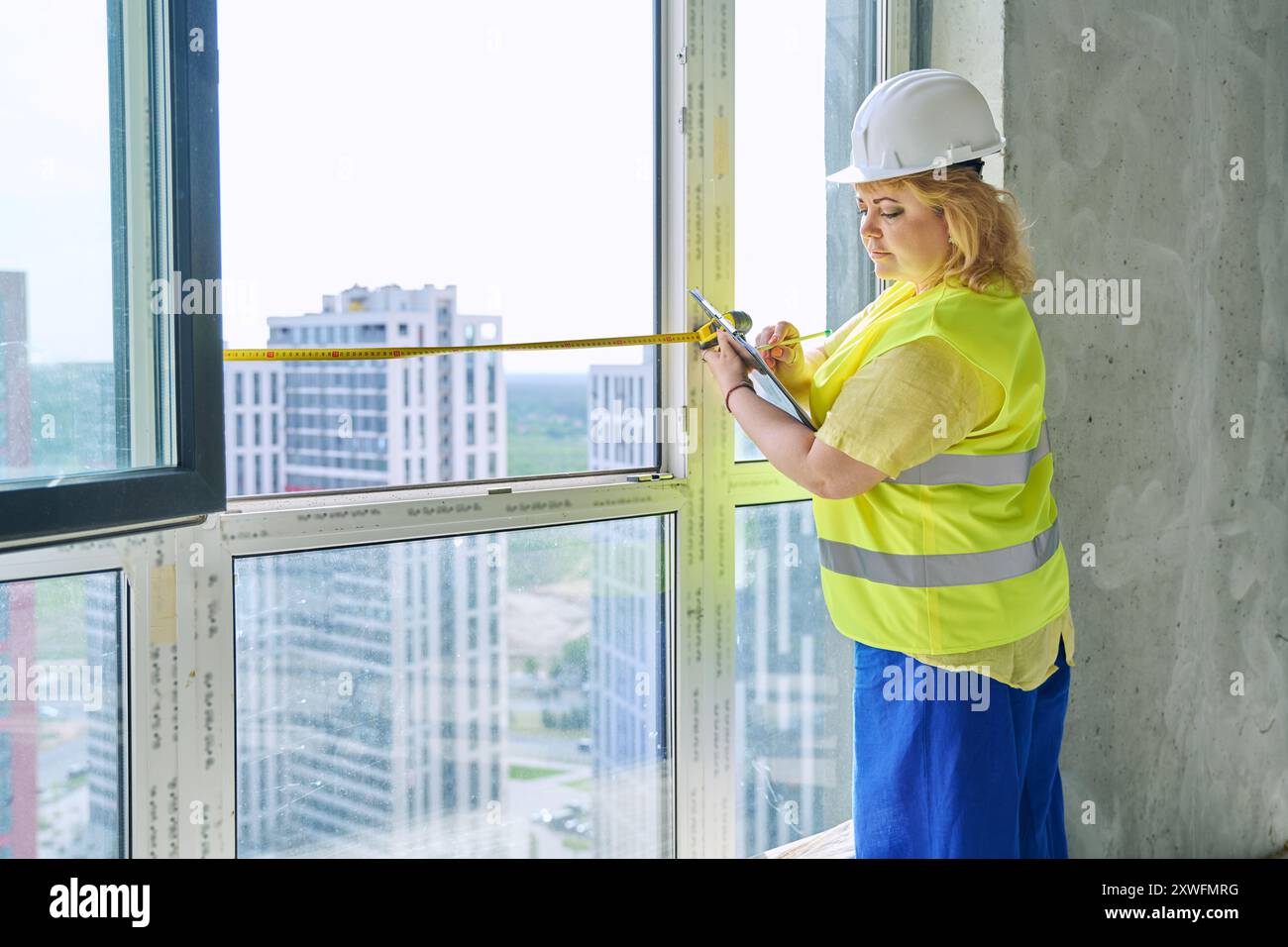 Female window decorator designer measuring window with tape measure ...