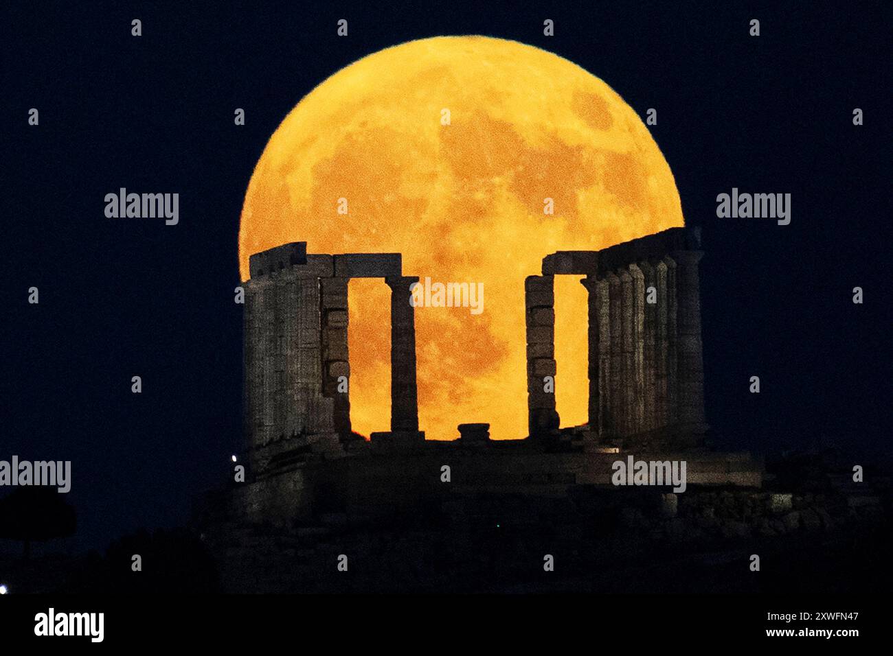 The super moon rises behind the Temple of Poseidon at Cape Sounio ...